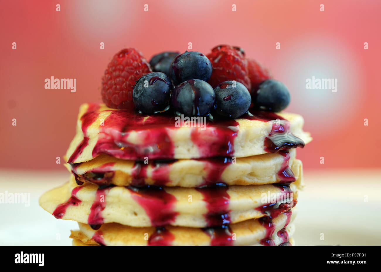 Stack of pancakes with raspberries, blueberries and drizzled with ...