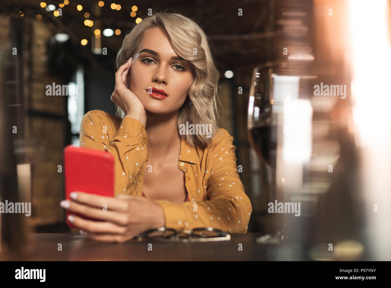 Charming young woman posing while sitting at bar and texting Stock ...