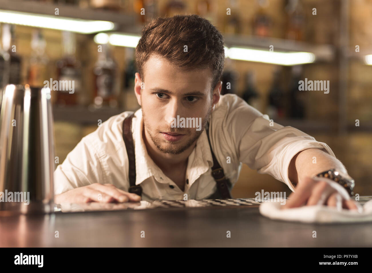 Pleasant young man cleaning bar counter thoroughly Stock Photo - Alamy