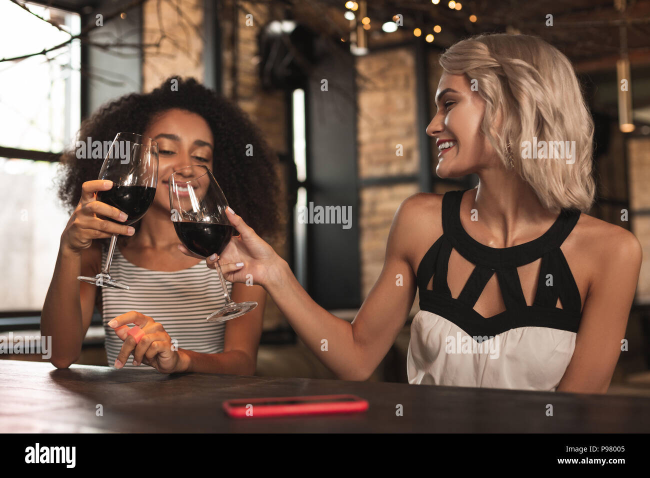 Beautiful young women drinking wine together Stock Photo - Alamy