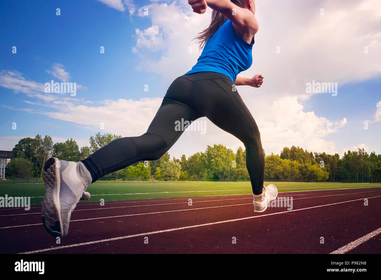 young fitness woman runner running on stadium track. The time of the ...