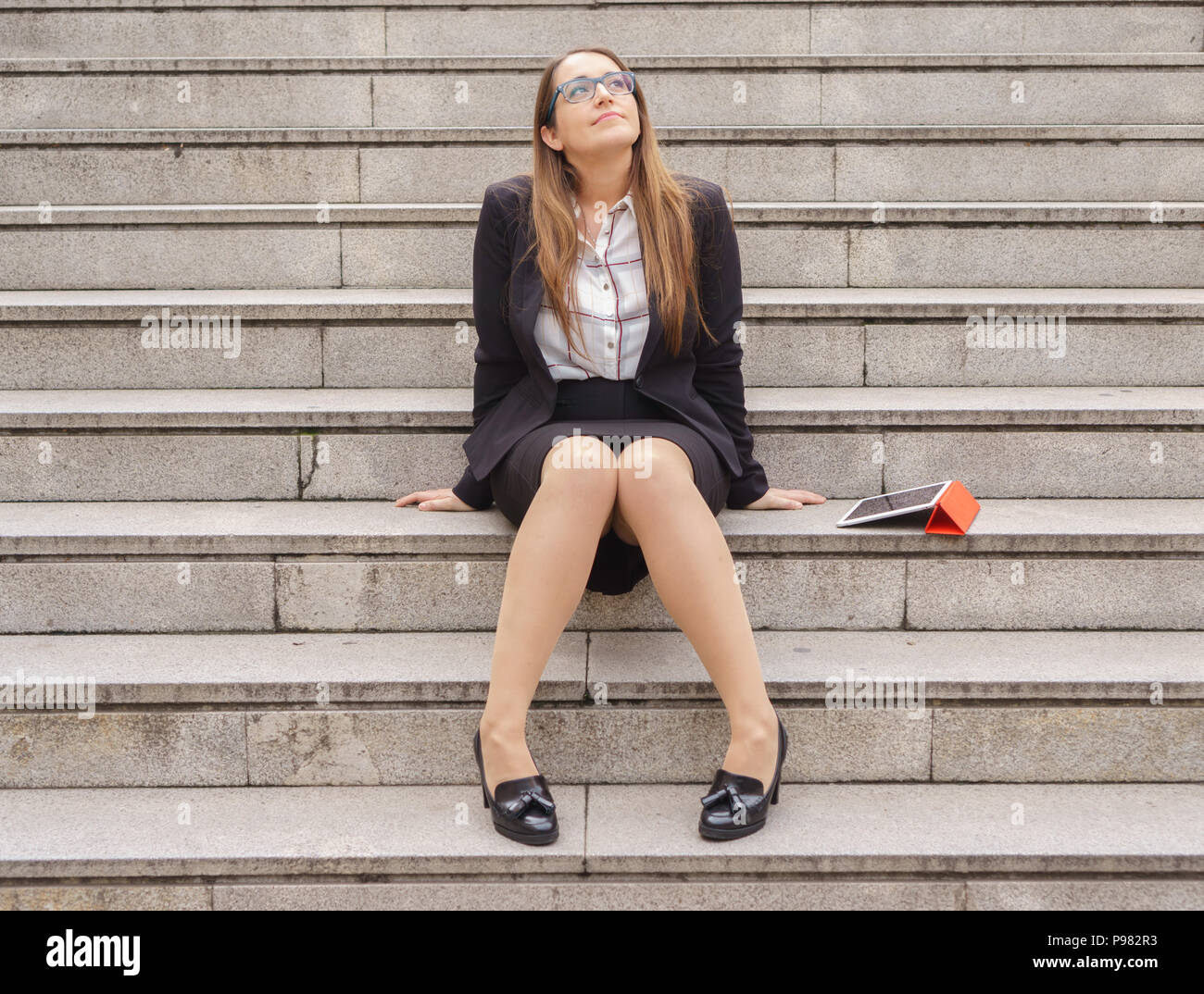 Office woman thinking in the stairs with tablet Stock Photo - Alamy