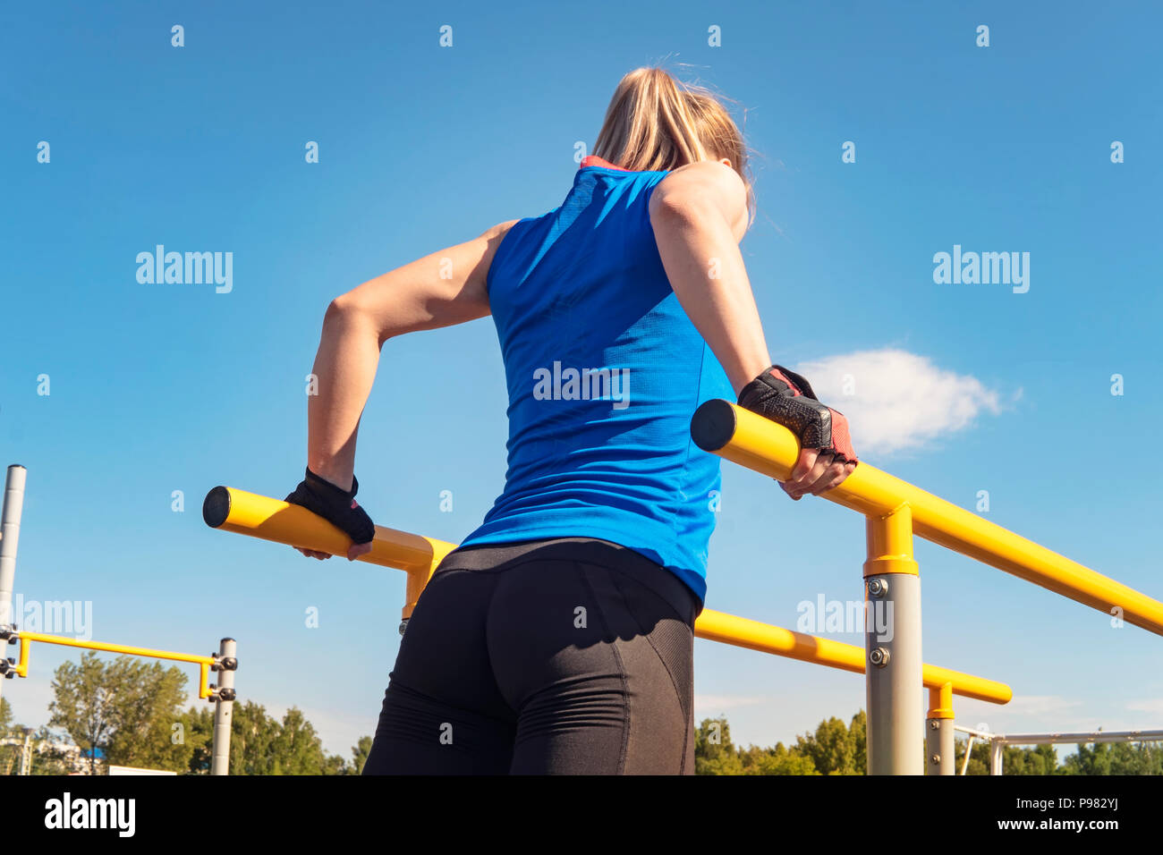 Fit young woman holding balance on the parallel bars. Blonde girl ...