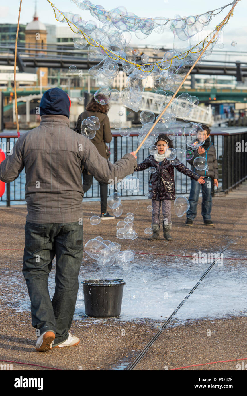 A street entertainer making bubbles to entertain the public on the ...