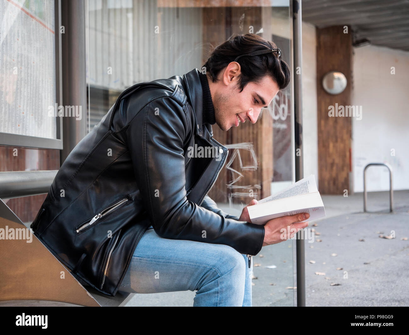 Casual man reading book on bench Stock Photo - Alamy