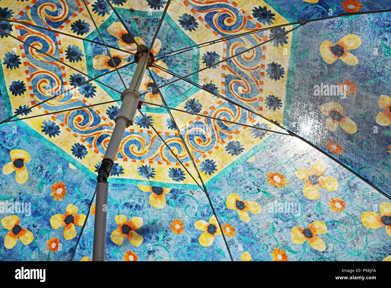 A multi-patterned parasol erected with bright sunlight passing through ...