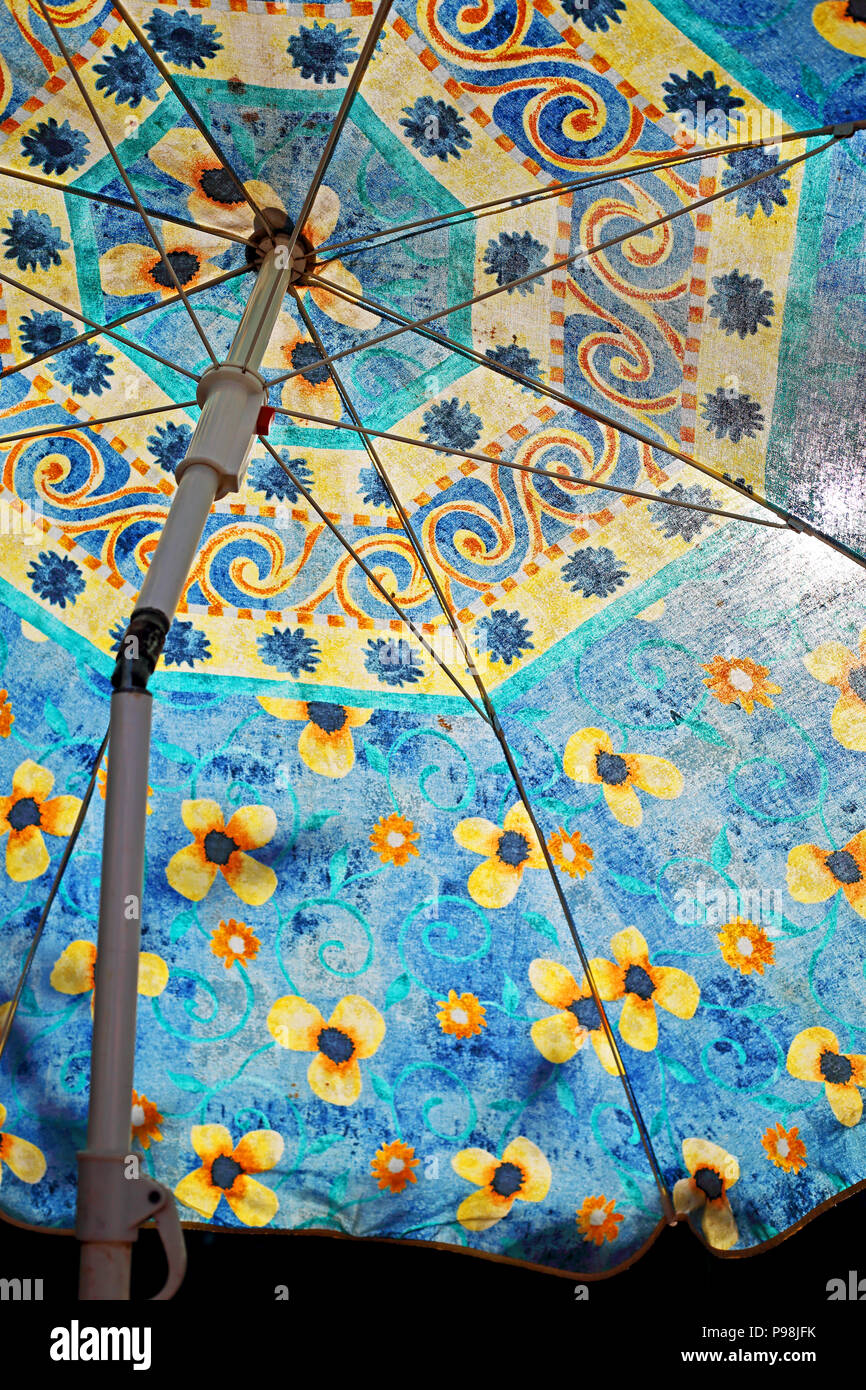 A multi-patterned parasol erected with bright sunlight passing through ...