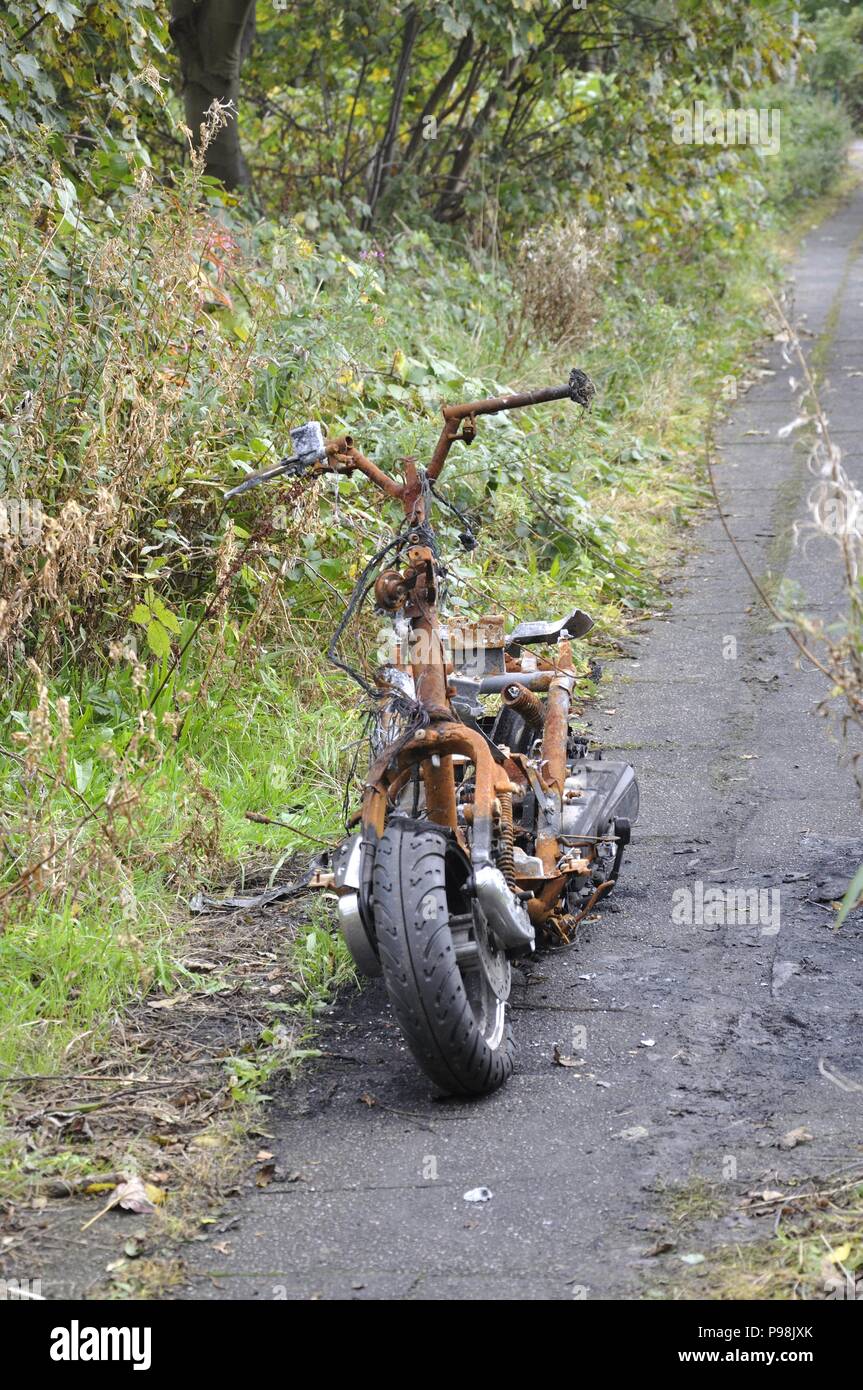 Burnt out motor cycle scooter on path Stock Photo - Alamy