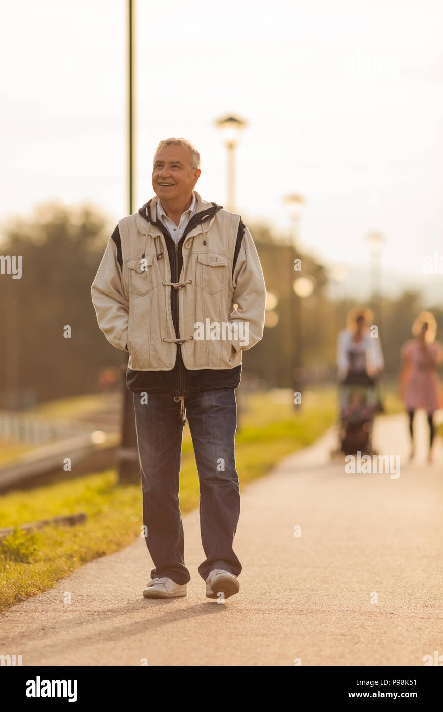 Happy senior man walking on the promenade Stock Photo - Alamy