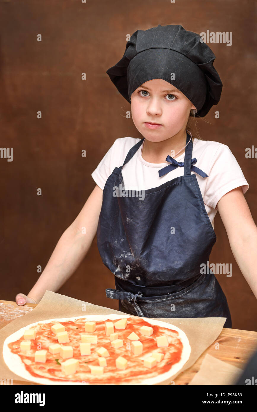 Little girl cook in uniform prepares pizza in the kitchen Stock Photo ...