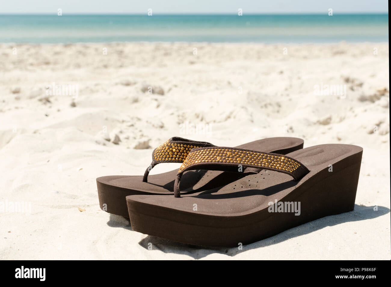 Flip flops in the sand on sea beach background Stock Photo - Alamy