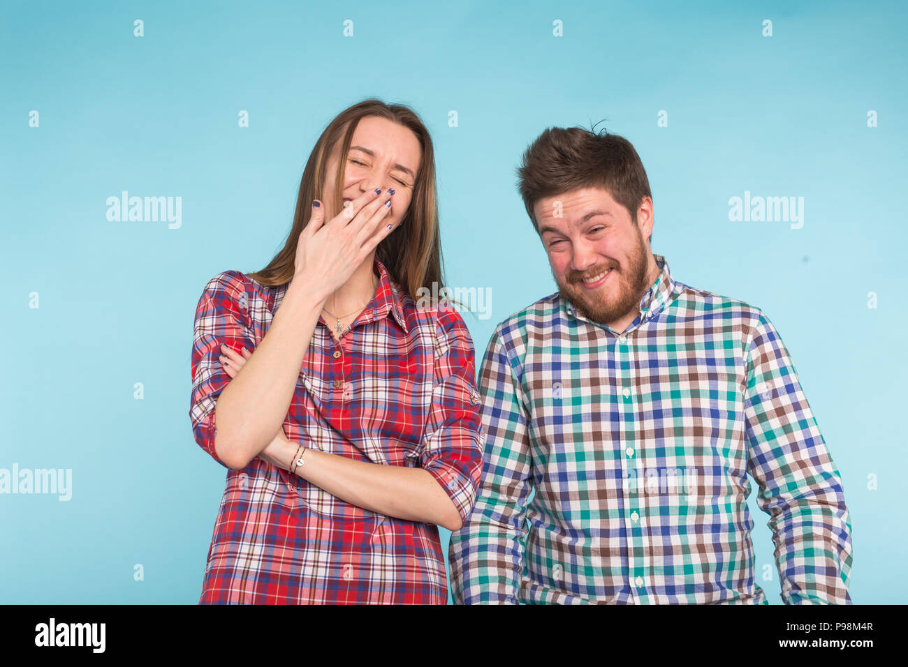 Funny young couple laughing and fooling around together on blue ...
