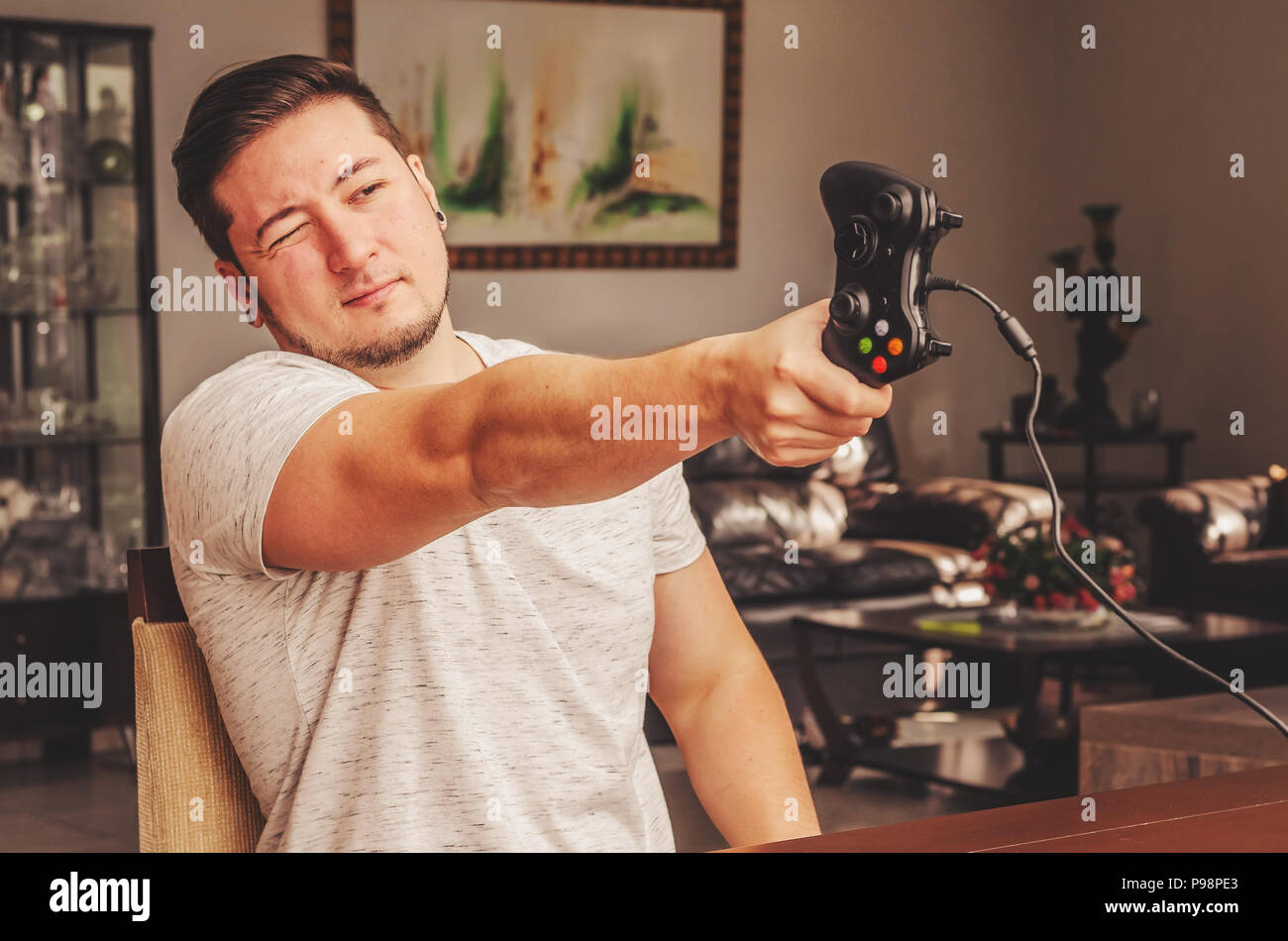 Gamer man holding a video game control like a gun Stock Photo - Alamy