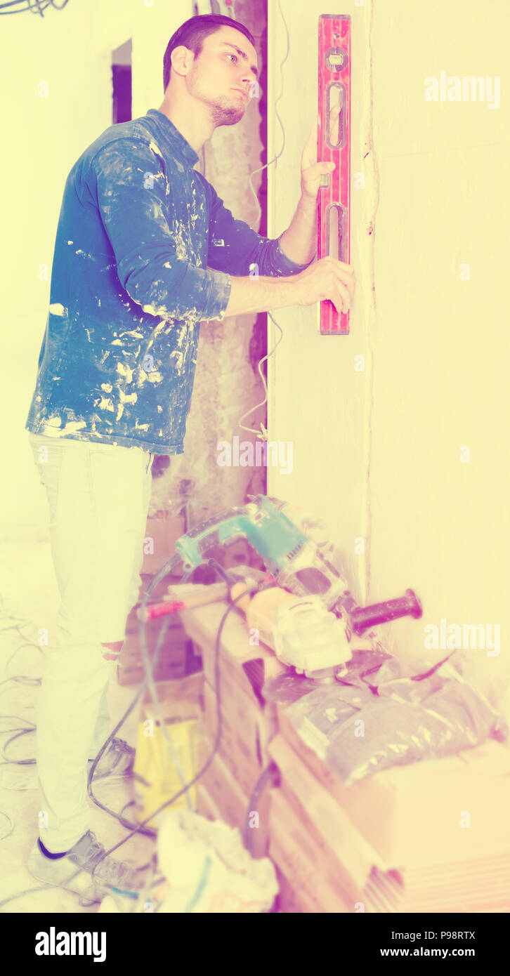 Builder is measuring angle of wall with level during house renovation ...