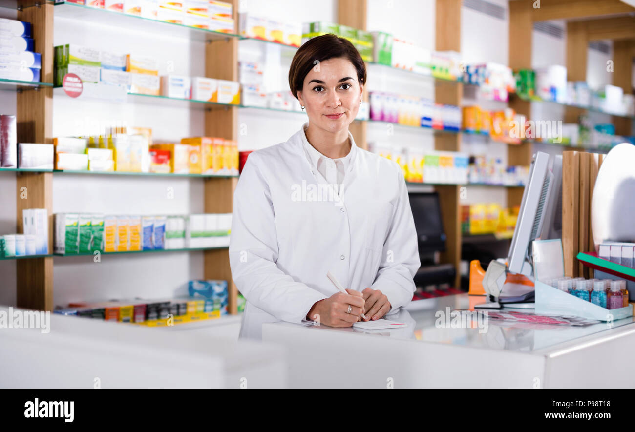 Young happy cheerful positive female pharmacist offering help in ...