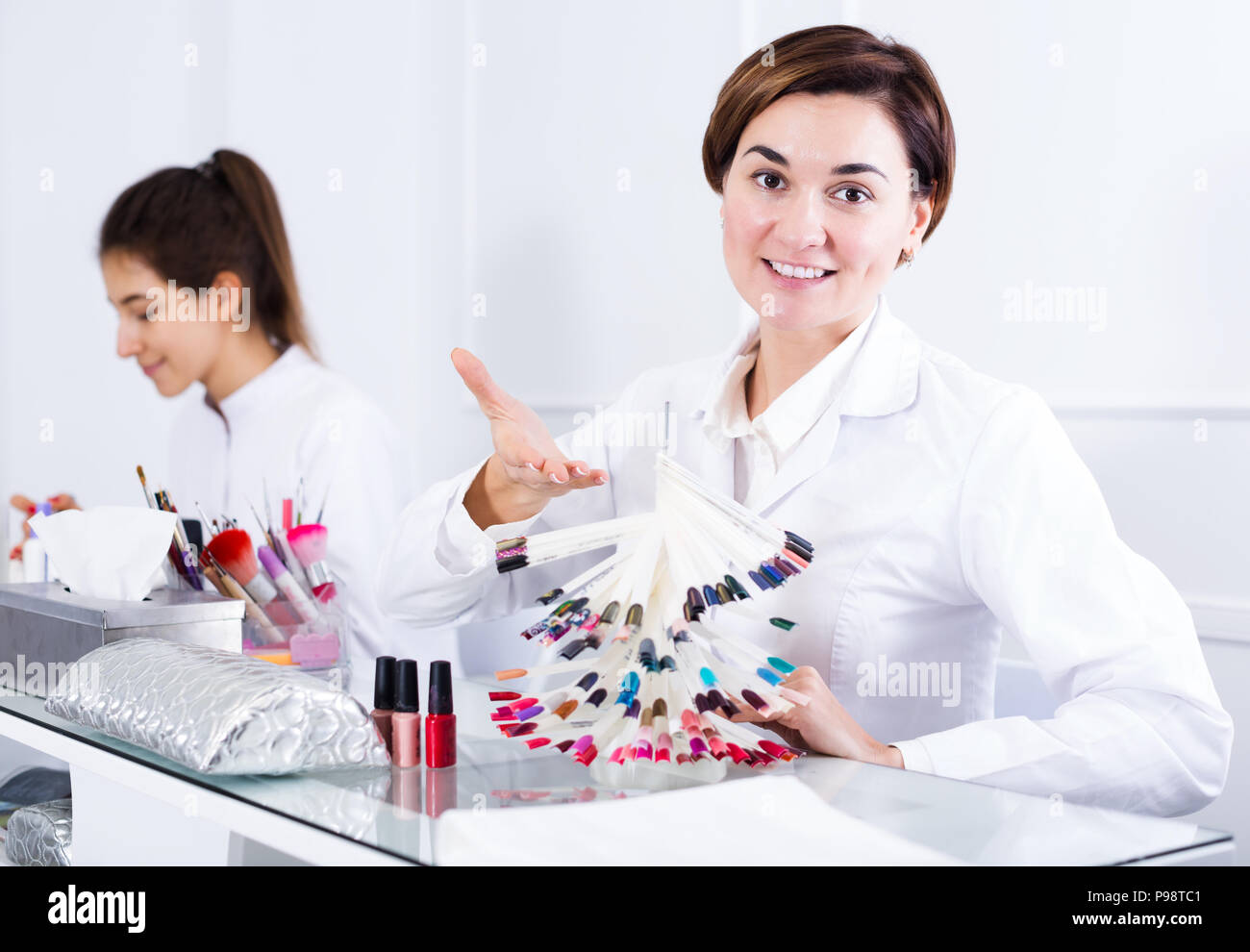 Pretty girl doing nails displaying her workplace in nail salon Stock ...