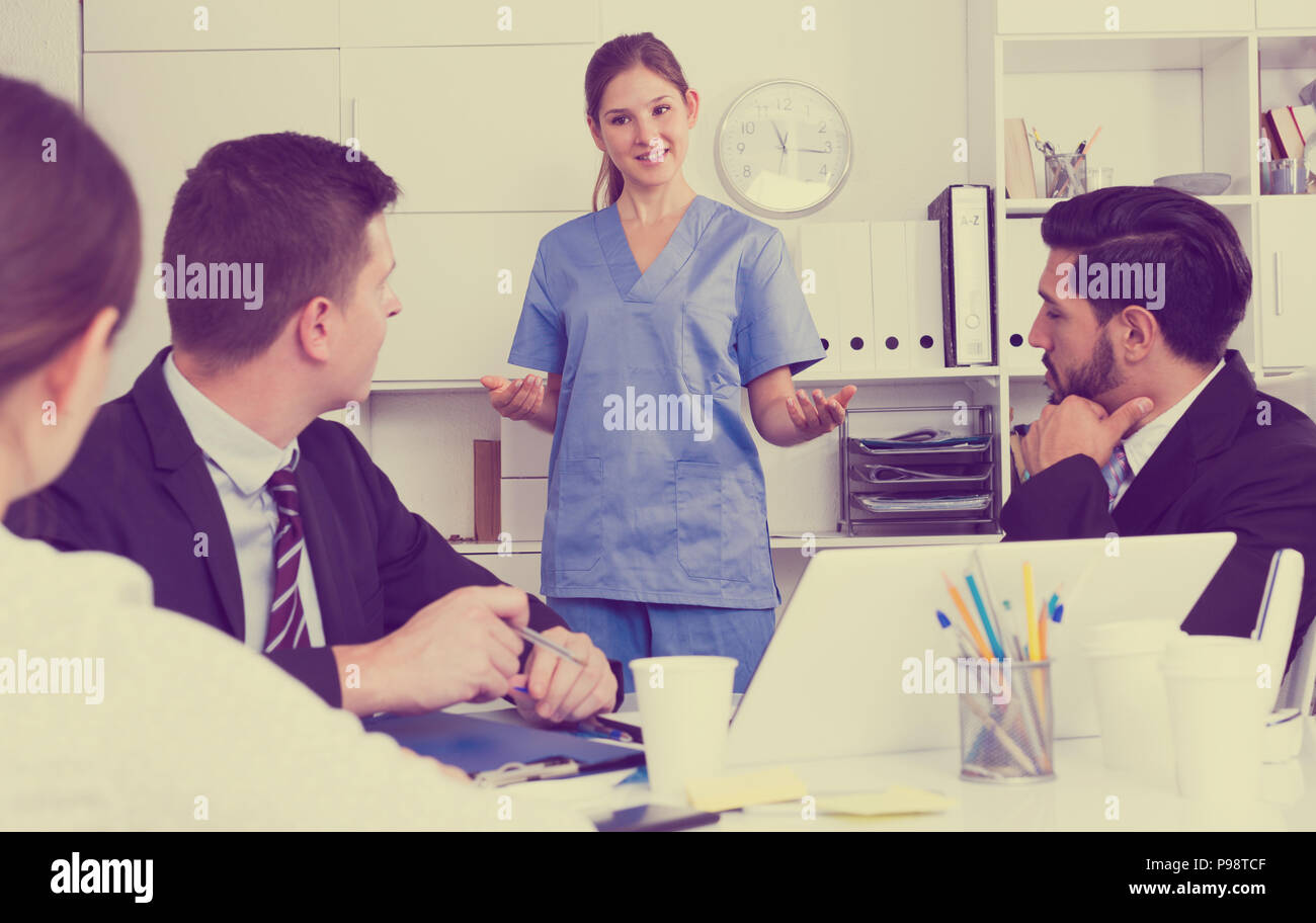 Young female medical worker telling office staff about first aid Stock ...