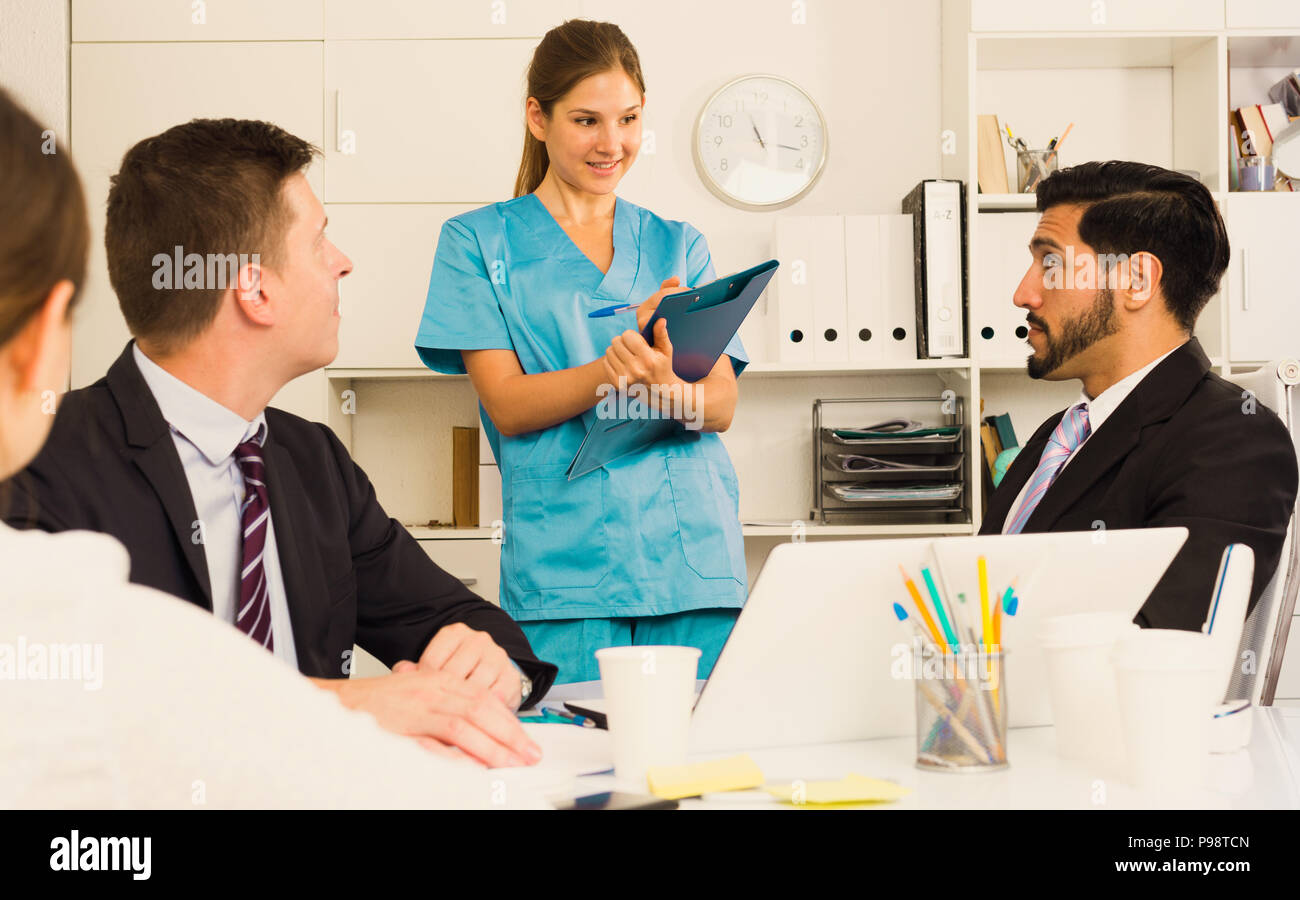 Young female medical worker telling office staff about first aid Stock ...