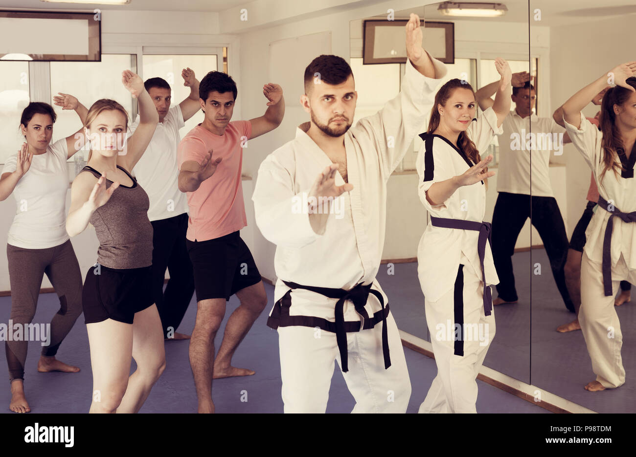 Cheerful people trying new martial moves in practice during karate ...