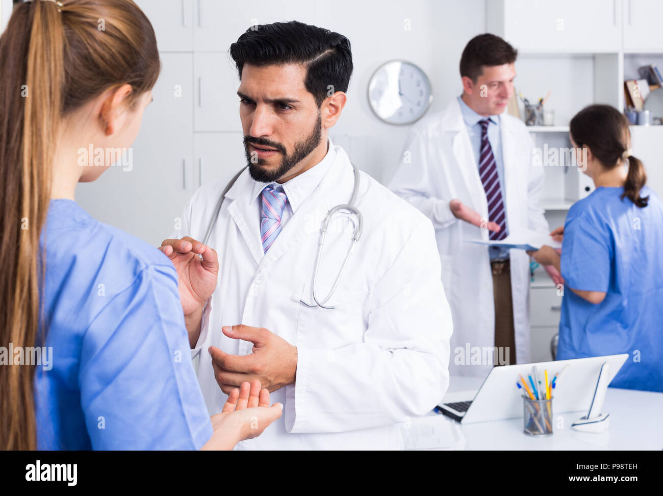 Doctor giving his younger female colleague piece of advice concerning ...