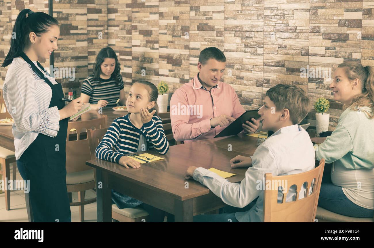 Happy waitress taking order from guests and writing into note Stock ...