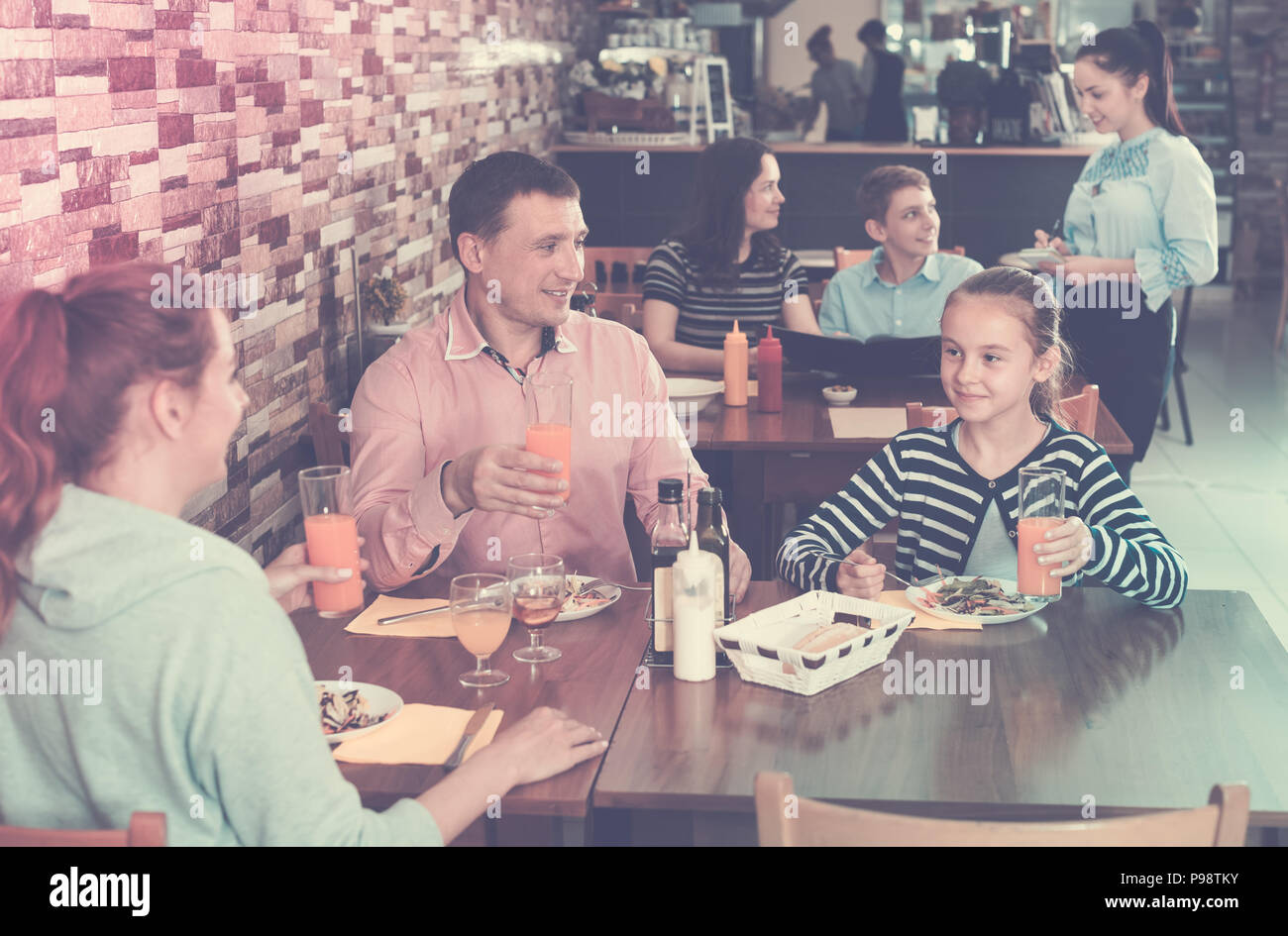 Smiling parents with children having conversation at dining table in ...