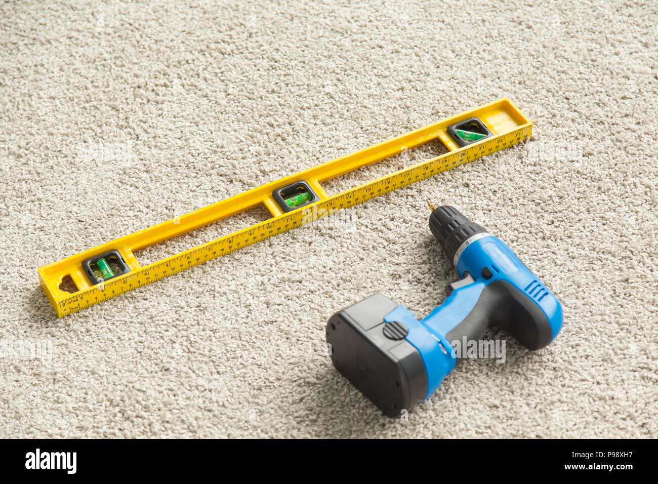 Builders level and drill on the floor, top view Stock Photo - Alamy