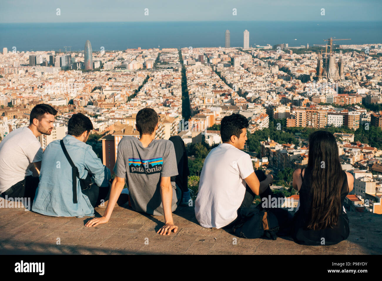 a young group of tourists sit atop Bunquers del Carmel at sunset, a ...