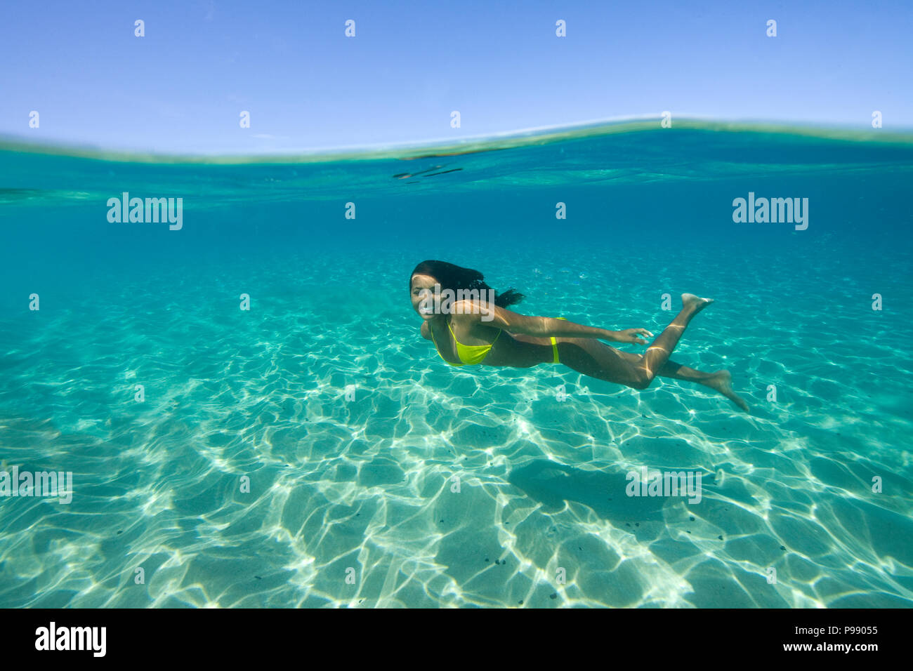 Split level view of a healthy female swimming underwater at Black Rock ...