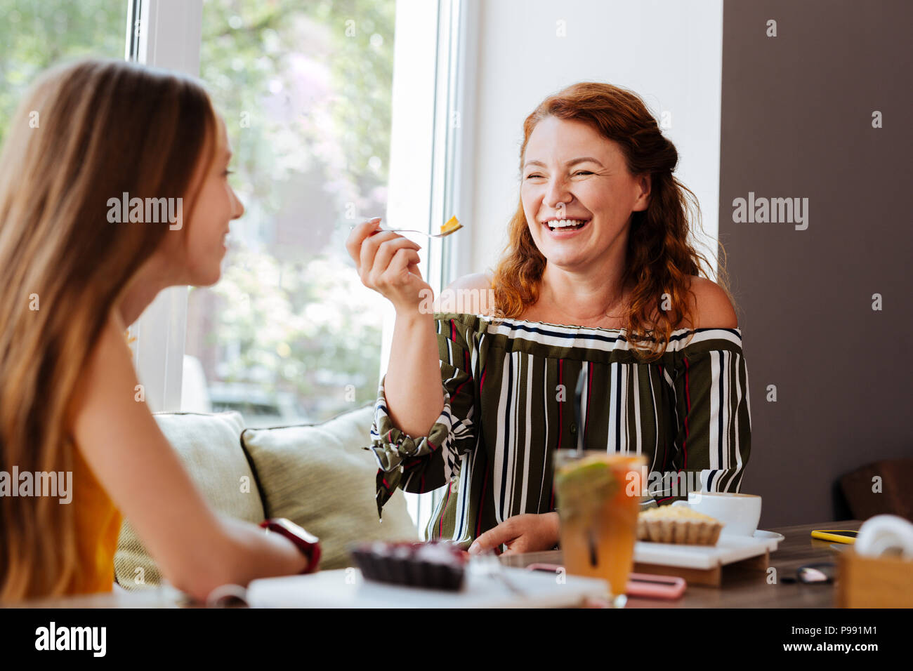 Red-haired woman laughing while talking to daughter Stock Photo - Alamy