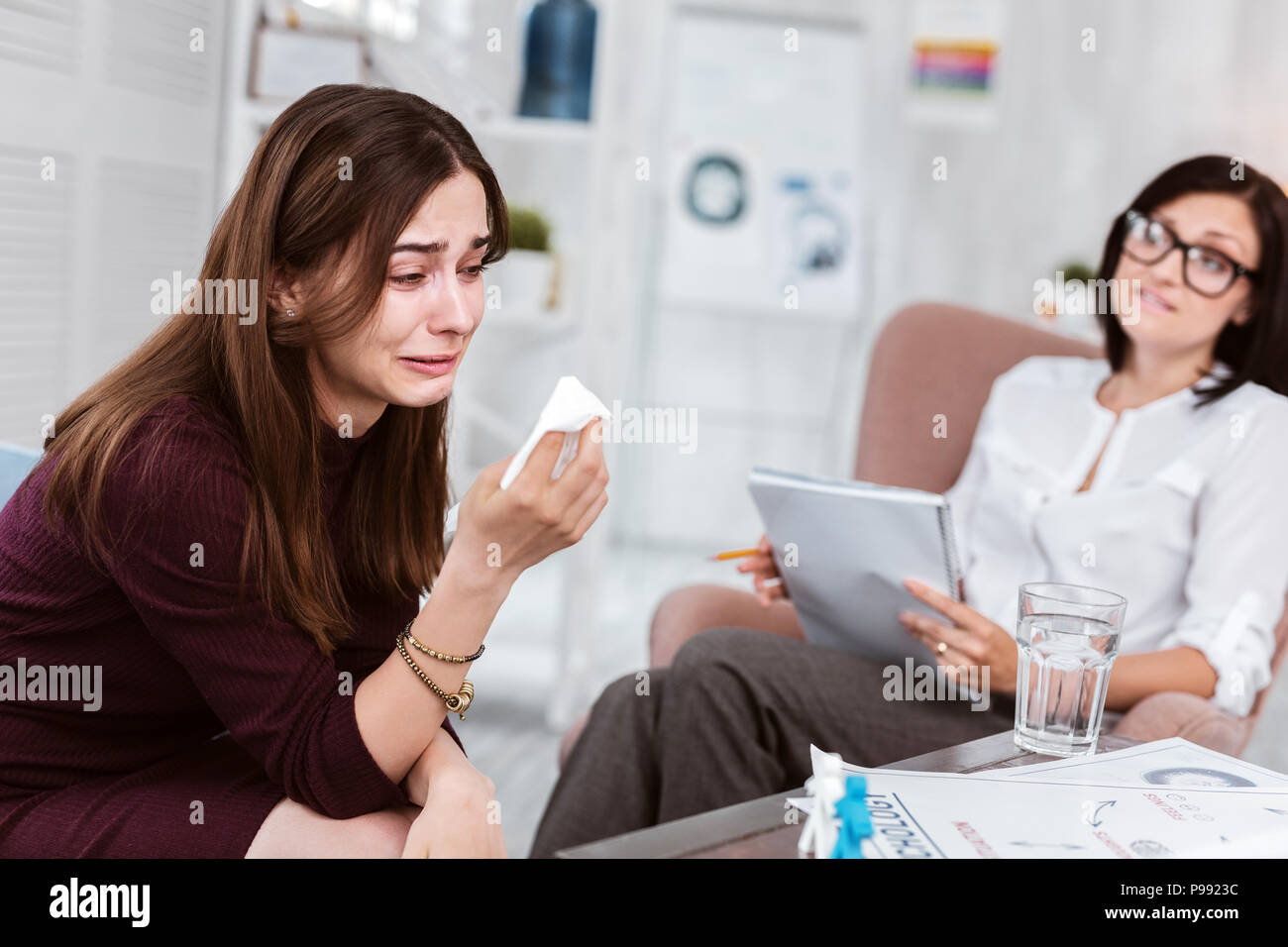 Sad person holding a napkin and crying while talking Stock Photo - Alamy