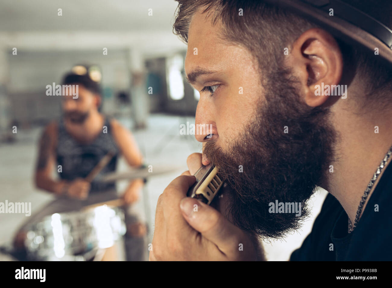 Repetition of rock music band. man with harmonica and drummer behind ...