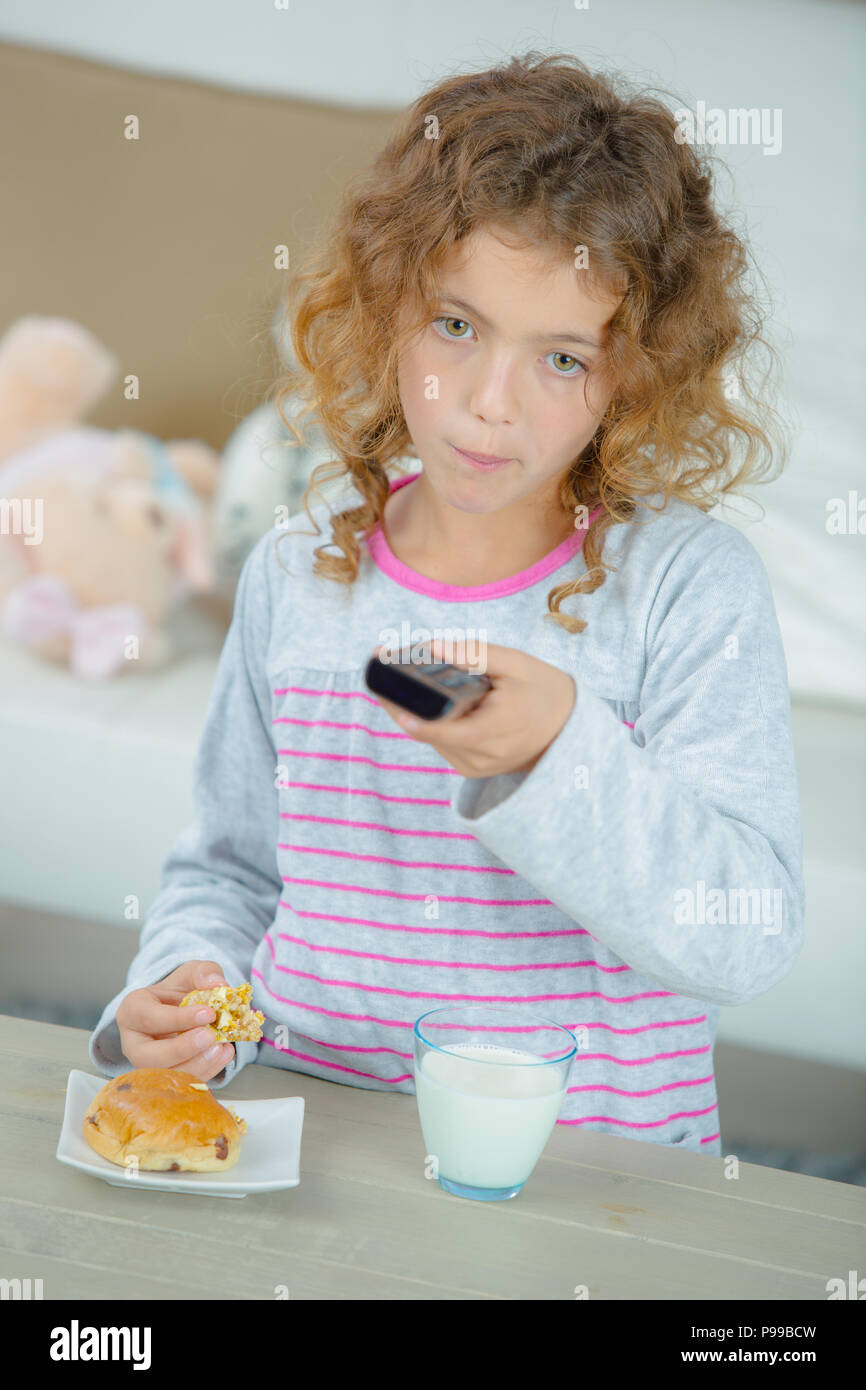 girl holding remote control while eating Stock Photo - Alamy