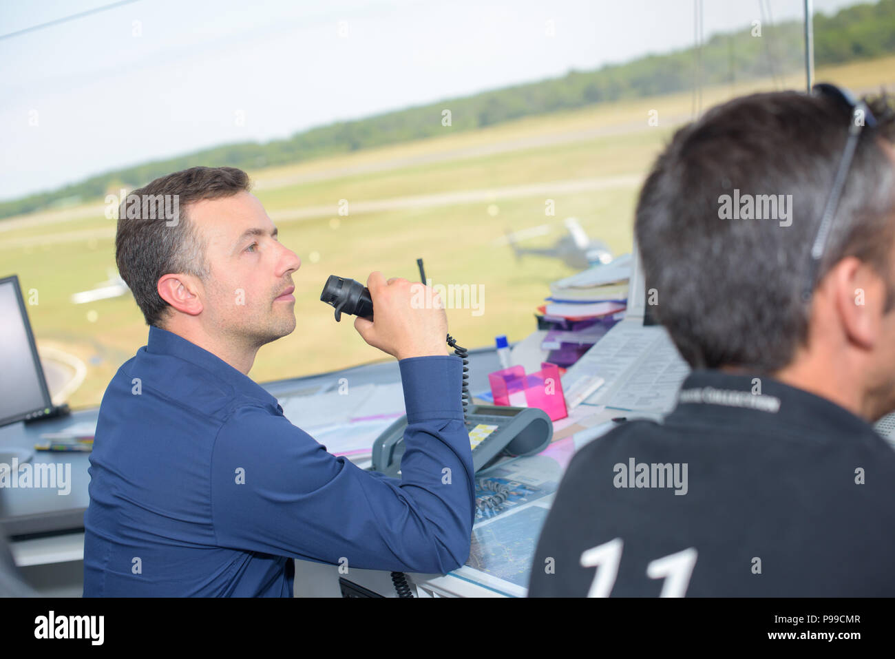 Control tower worker talking into receiver Stock Photo - Alamy