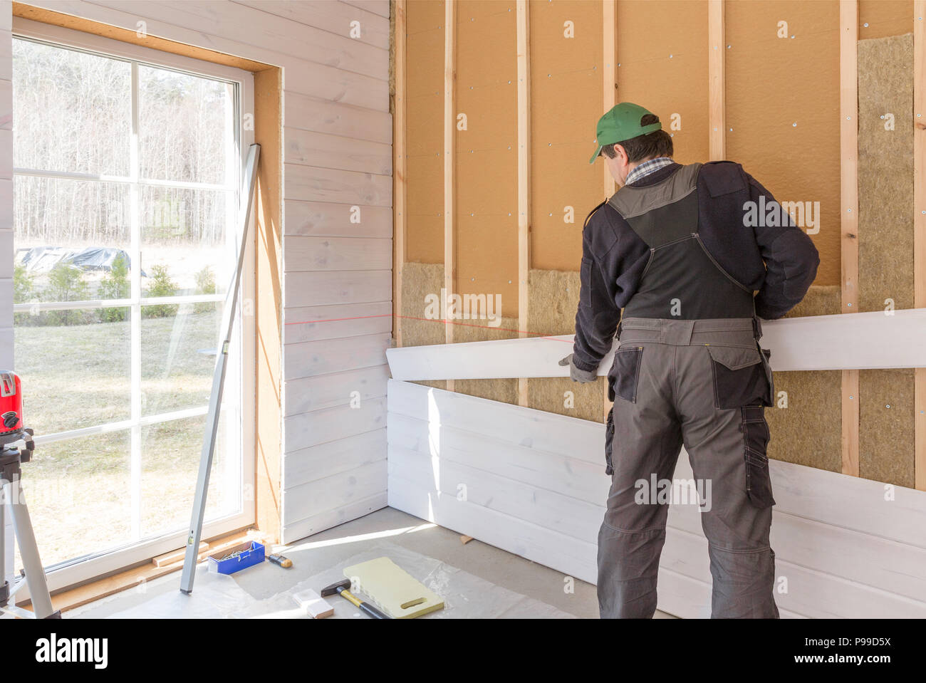 The worker makes finishing works of walls with a white wooden board ...