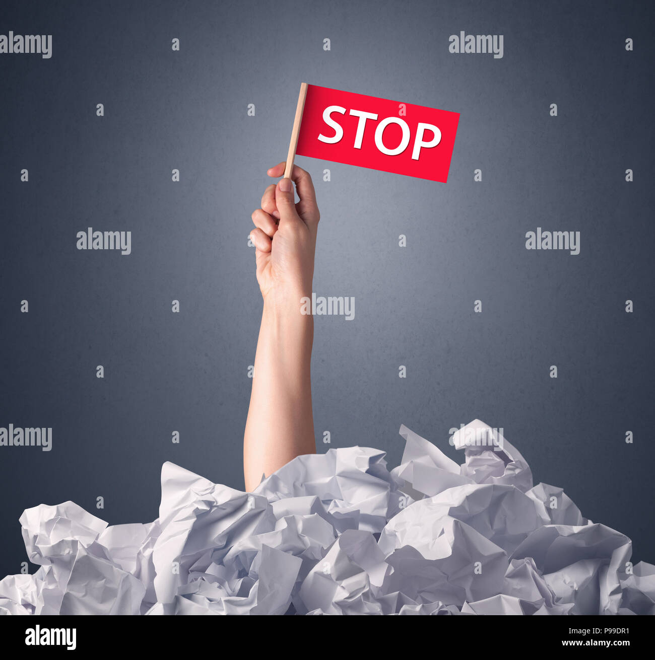 Female hand emerging from crumpled paper pile holding a red flag with ...