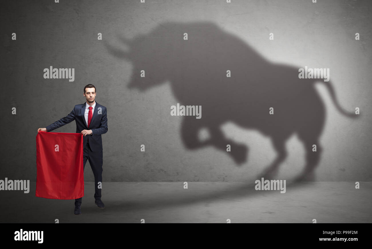 Businessman standing with red cloth in his hand and big bull shadow on ...