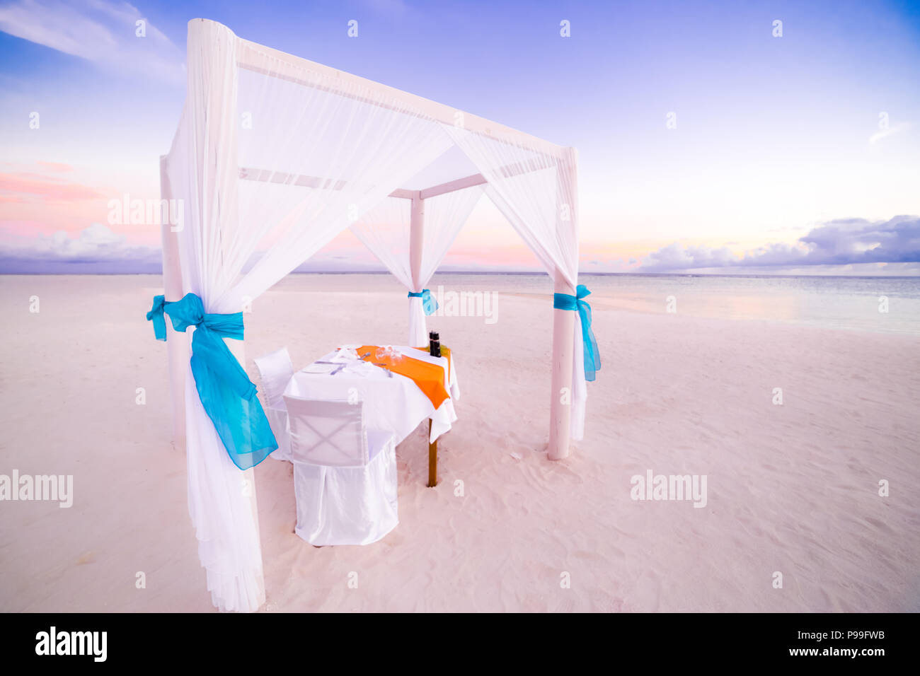 Romantic dinner table set-up for a honeymoon couple on the beach under ...