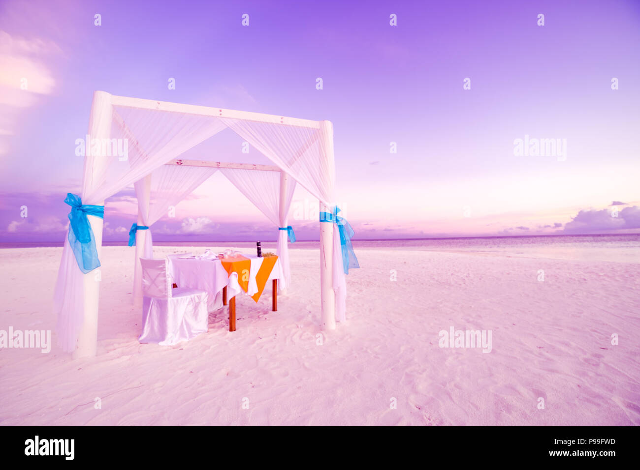 Romantic dinner table set-up for a honeymoon couple on the beach under ...