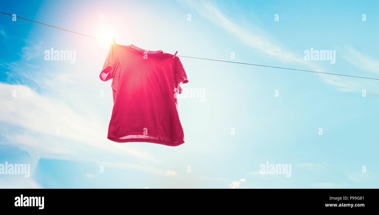 Red t-shirt on clothes line against sun and blue sky with clouds Stock ...