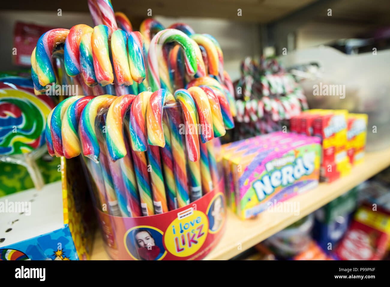 Bright rainbow-coloured traditional candy sticks on a packed sweet shop ...