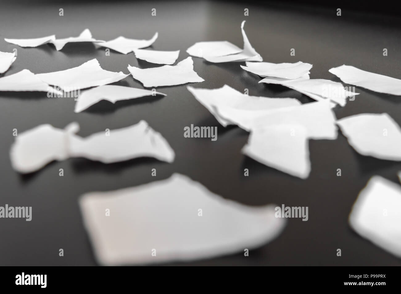 Papper torn in many pieces over a black surface Stock Photo - Alamy