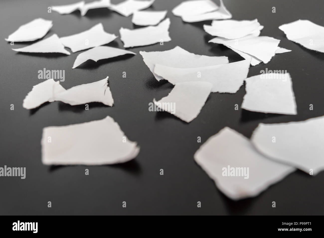 Papper torn in many pieces over a black surface Stock Photo - Alamy