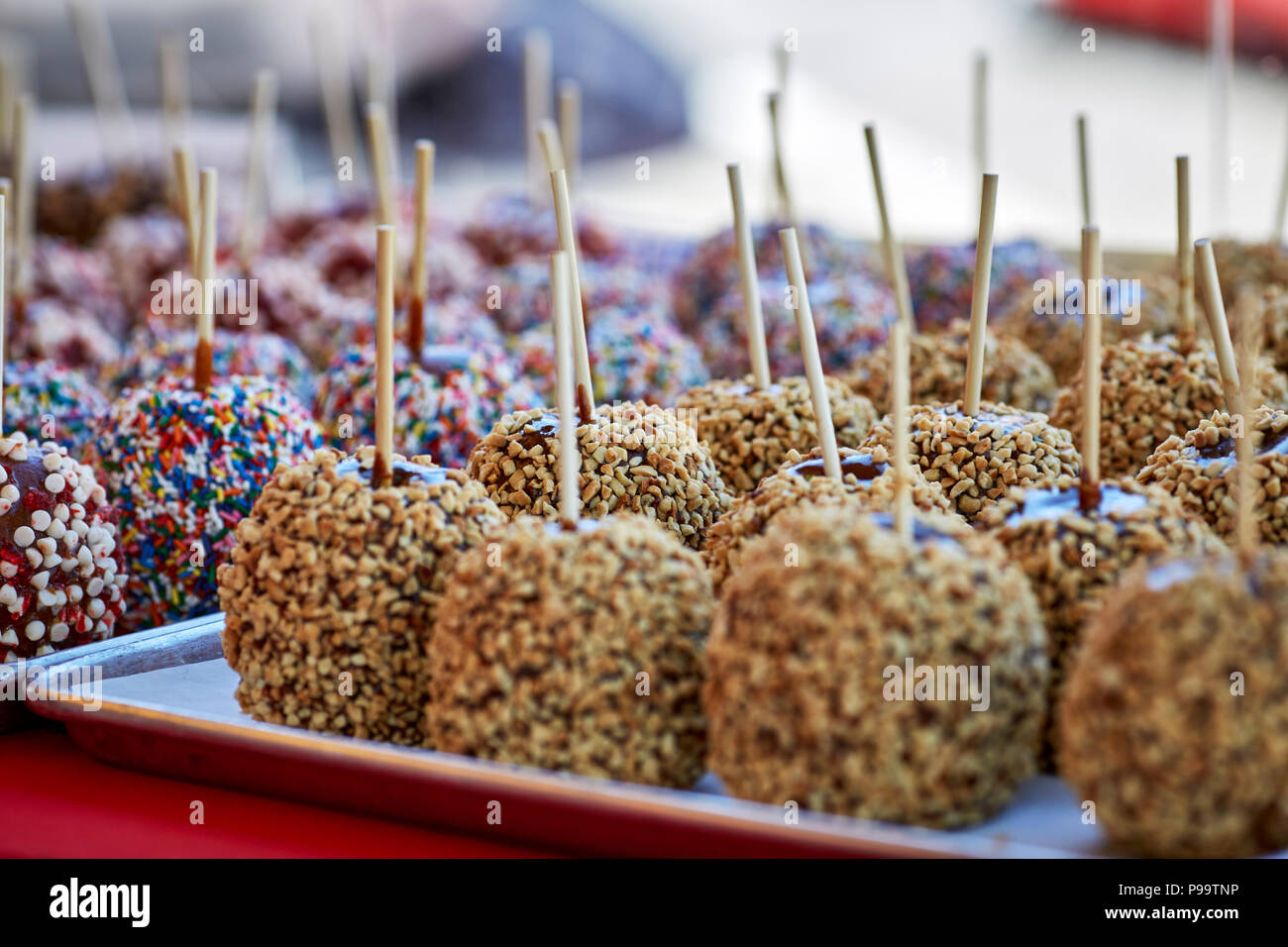 Candied apples coated with chopped nuts on a stick with shallow depth ...