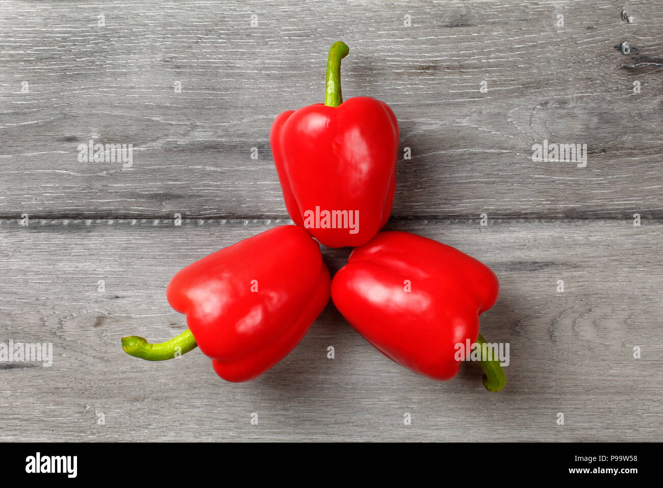 Table top view, three bright red bell peppers arranged into triangle ...
