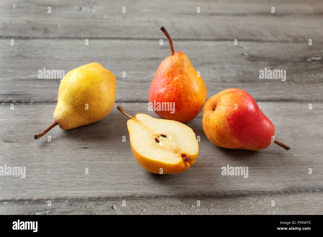 Four pears, one cut in half, on gray wood desk Stock Photo - Alamy