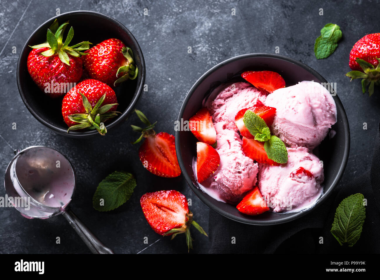 Strawberry ice cream with fresh berries in a bowl on black. Top view ...