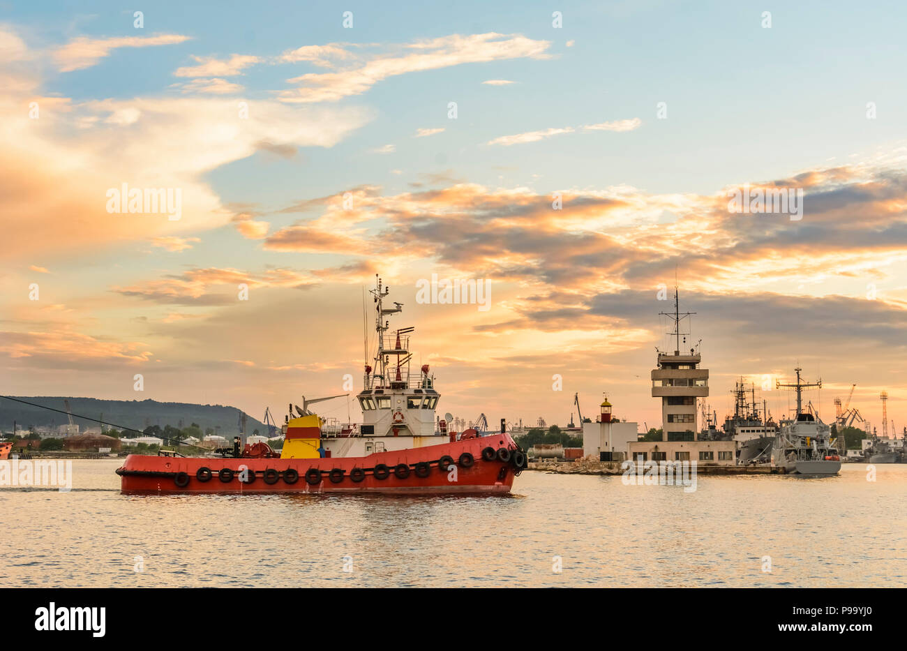 Tug boat entering the harbor with big cargo boat Stock Photo - Alamy