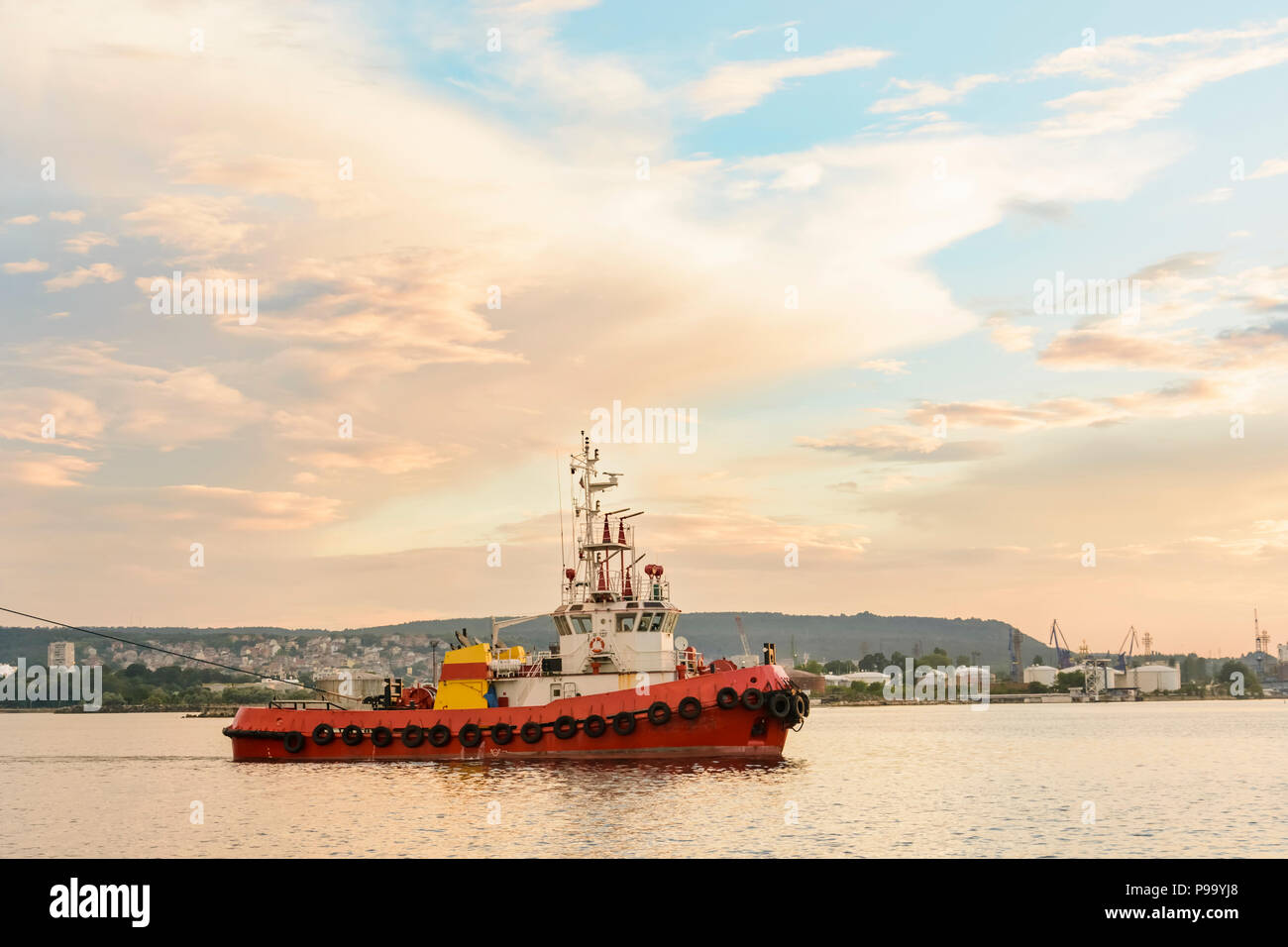 Tug boat entering the harbor with big cargo boat Stock Photo - Alamy