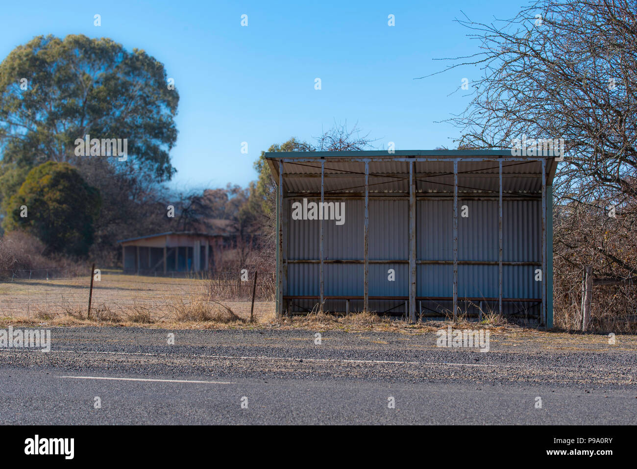 An empty corrugated (galvanized) iron covered bus stop beside the road ...